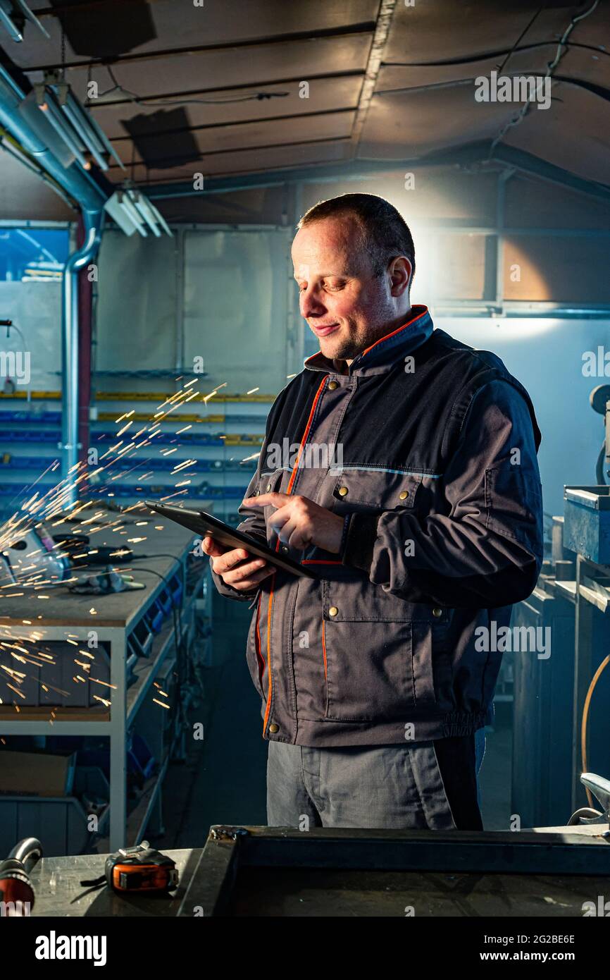 The handyman with a tablet in his workshop typing something, while in ...
