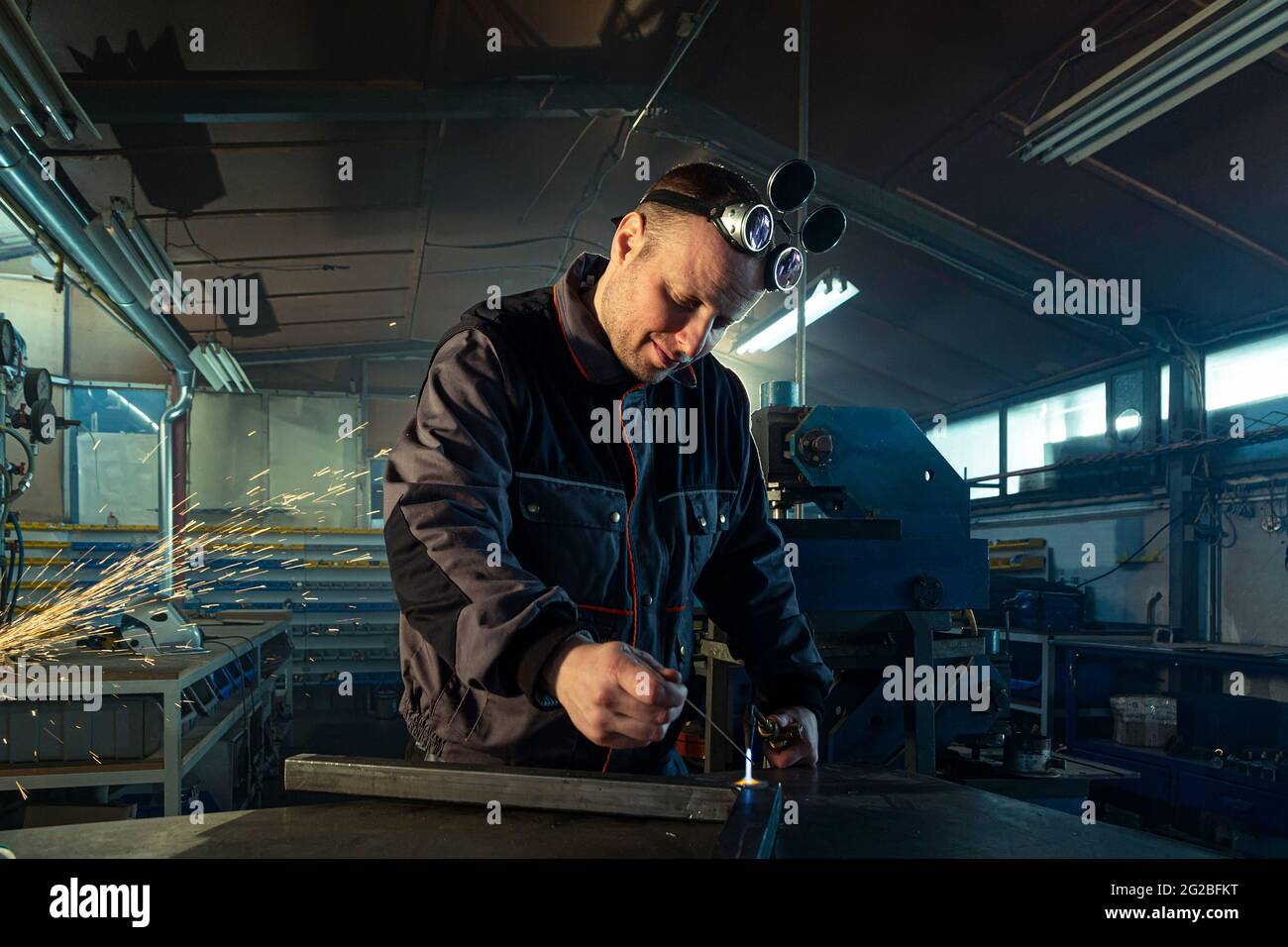 Welder working with autogenous welding tool in workshop while his ...