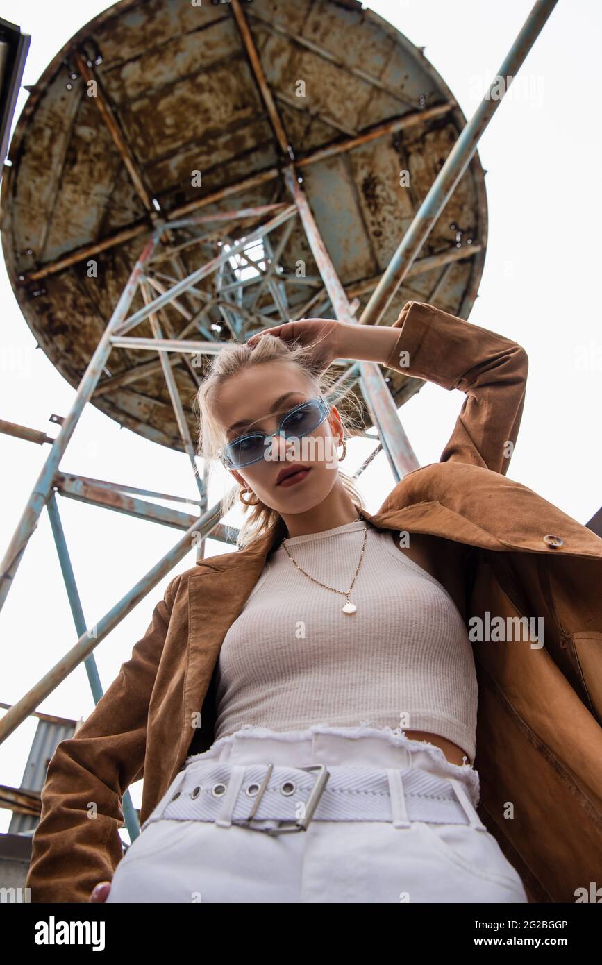 low angle view of young model in blue sunglasses posing near ...