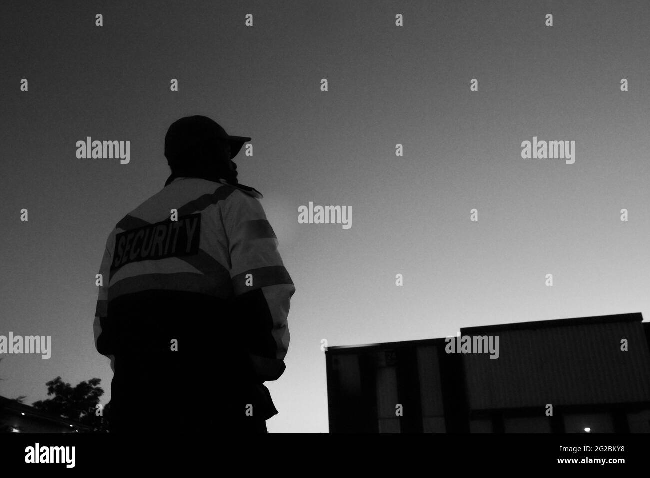 Grayscale shot of a security guard patrolling busy street and city at ...