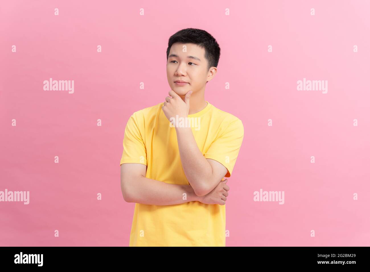 Young man holding chin as trying to solve some problem Stock Photo - Alamy