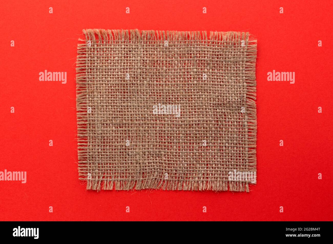 Old burlap napkin on red color background, top view Stock Photo - Alamy