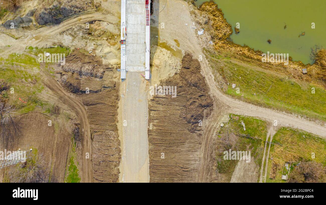 Above top view, overhead, on unfinished bridge, road over river is ...