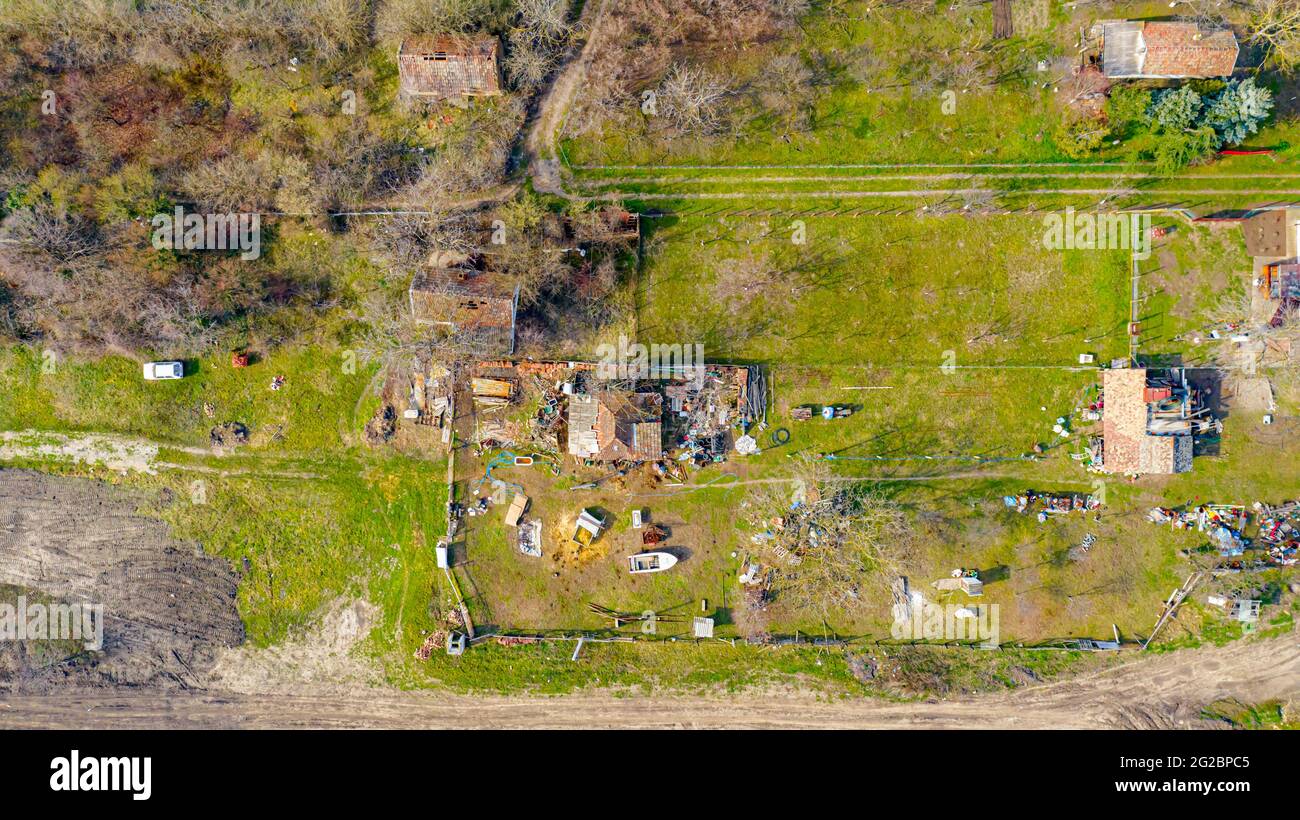 Above top view on fenced messy yard, old house with scattered things ...