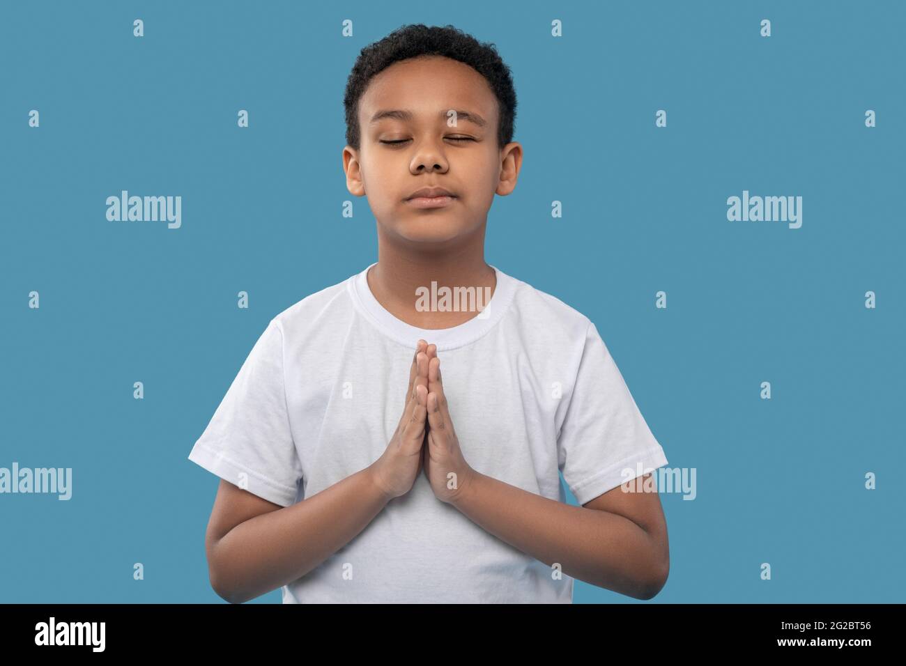 African american boy standing in namaste pose Stock Photo - Alamy
