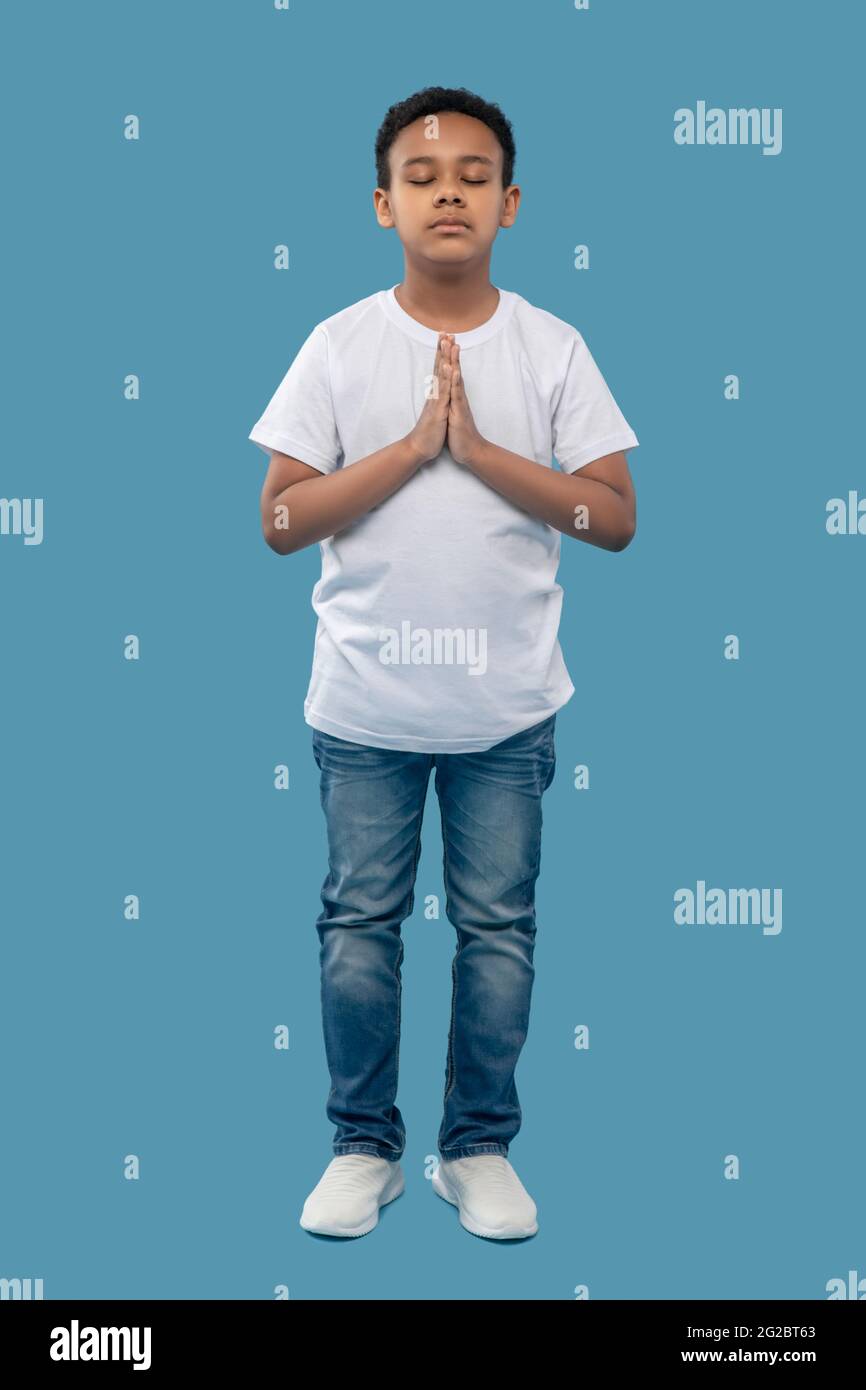 Calm boy with closed eyes doing namaste Stock Photo - Alamy