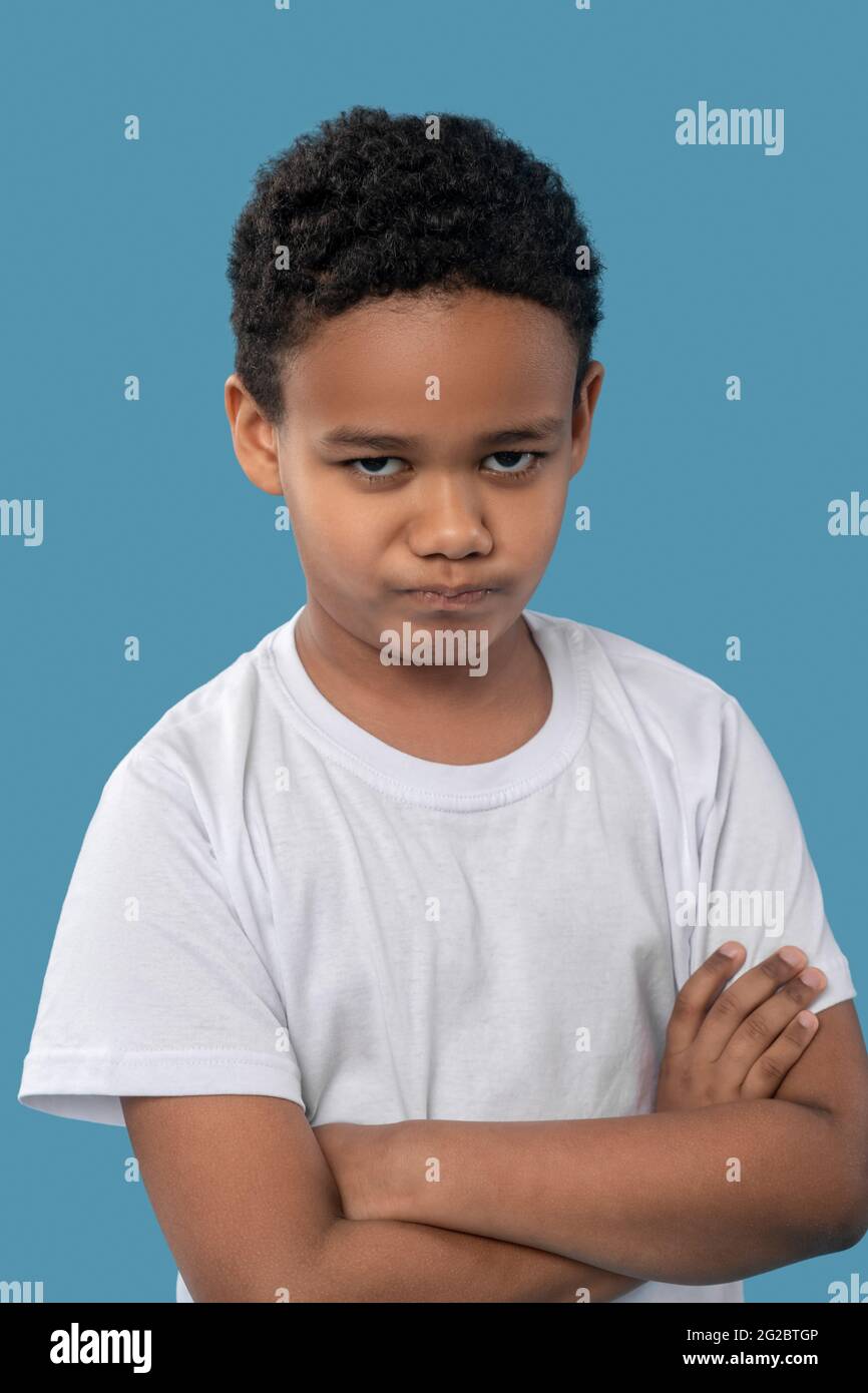 Angry dark skinned boy standing with folded hands Stock Photo - Alamy