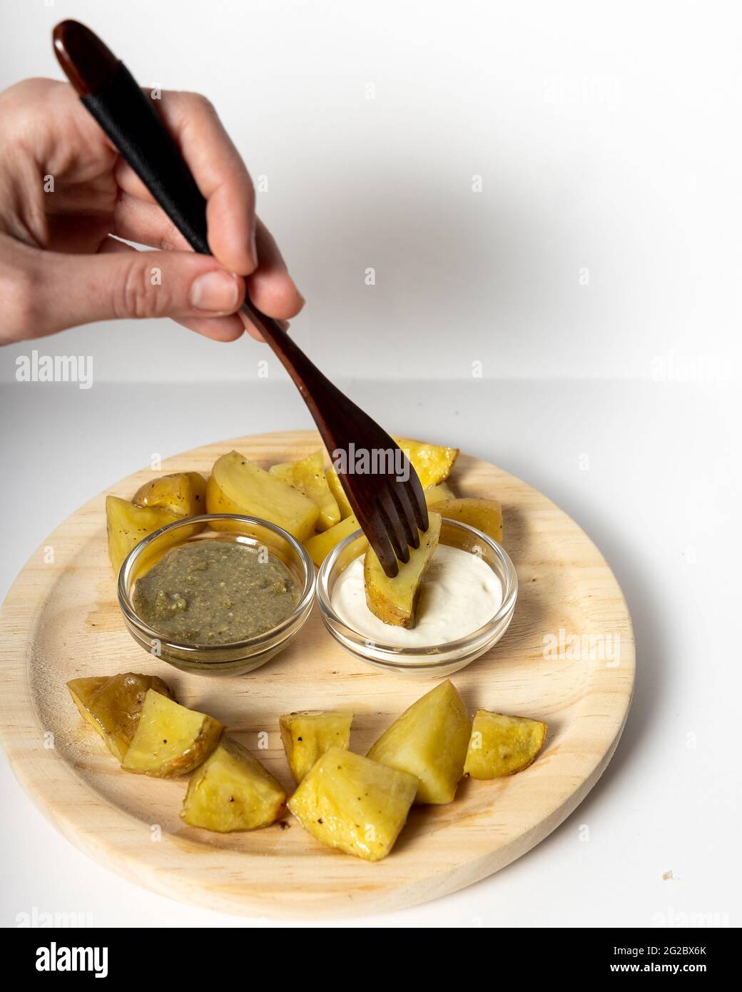 Closeup of a female dipping a piece of delicious fried potato into the ...