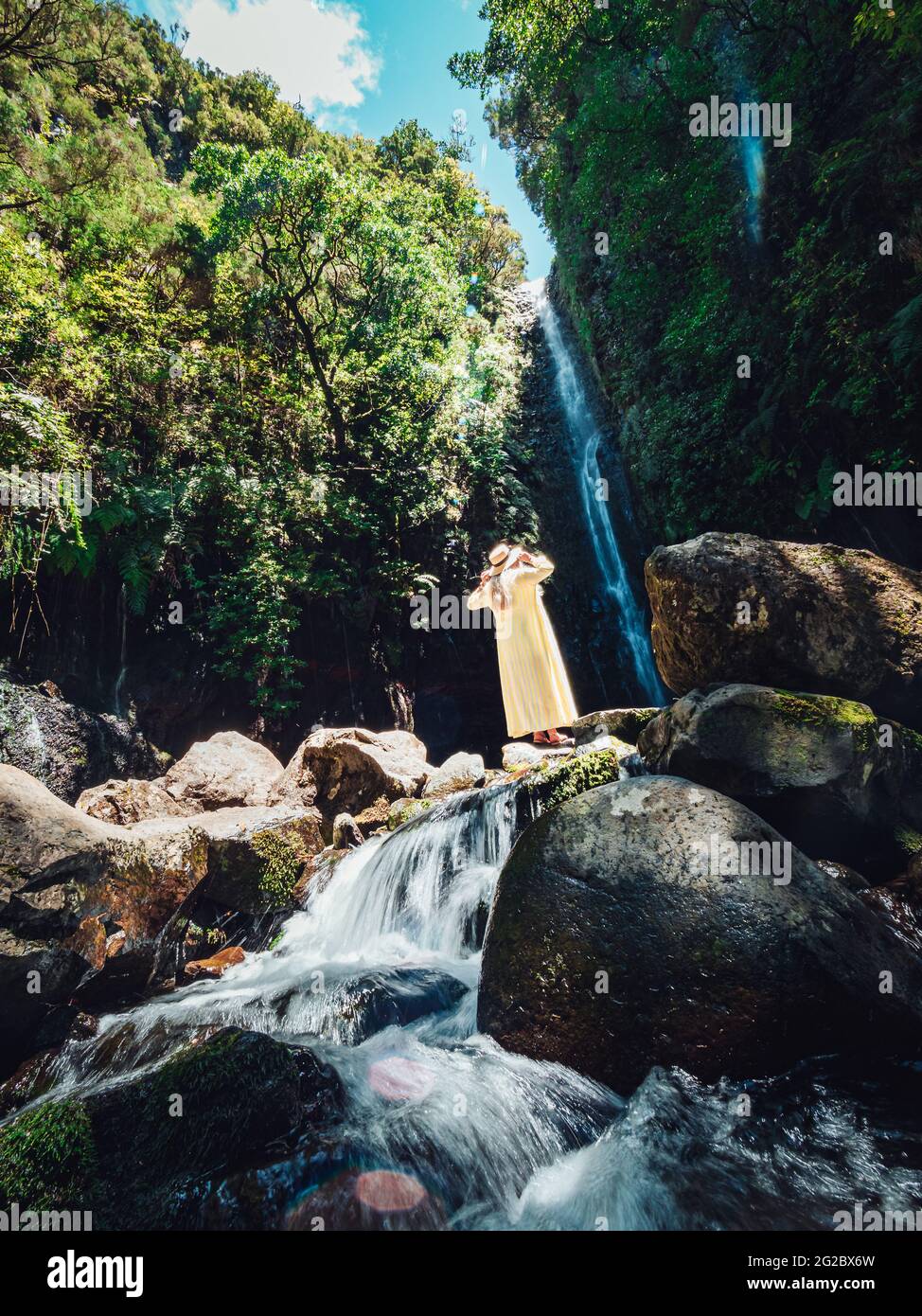 Vertical shot of a female in a yellow dress and hat standing on the ...
