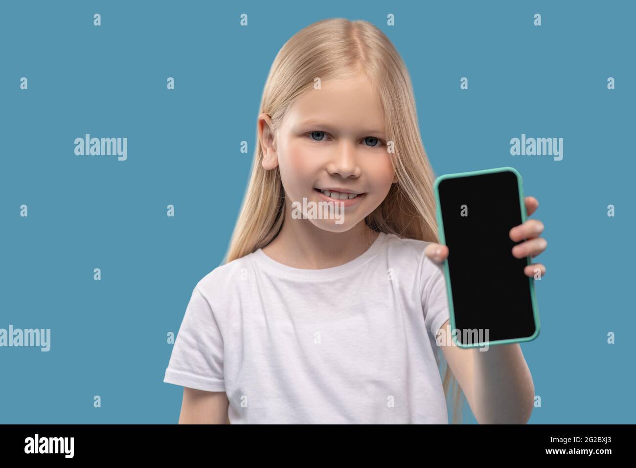 Little smiling girl showing smartphone screen Stock Photo - Alamy