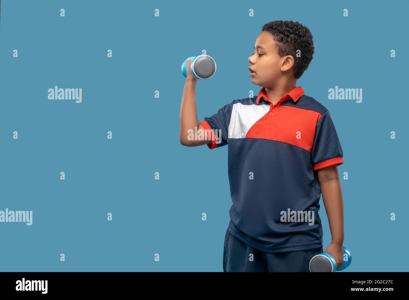 Serious african american boy doing dumbbell exercise Stock Photo - Alamy