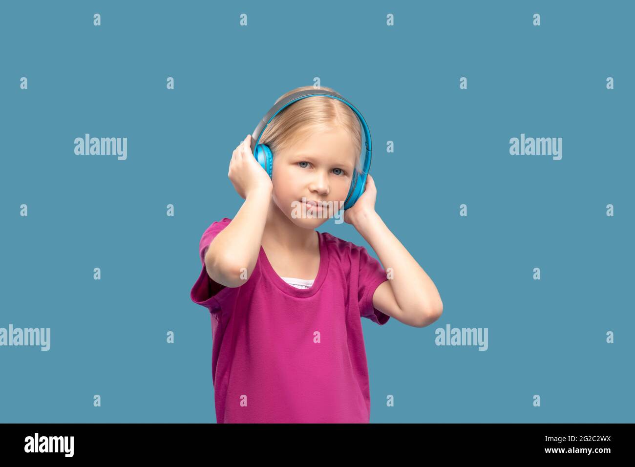 Cute blonde girl in blue headphones Stock Photo - Alamy