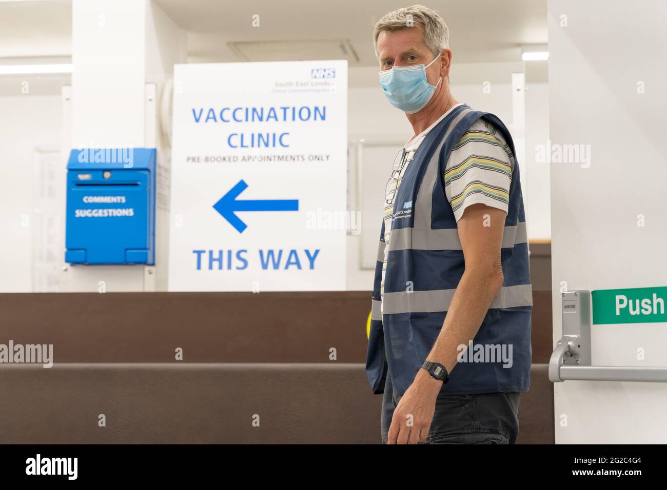 Volunteer man directing people to the NHS Covid-19 Vaccination clinic ...