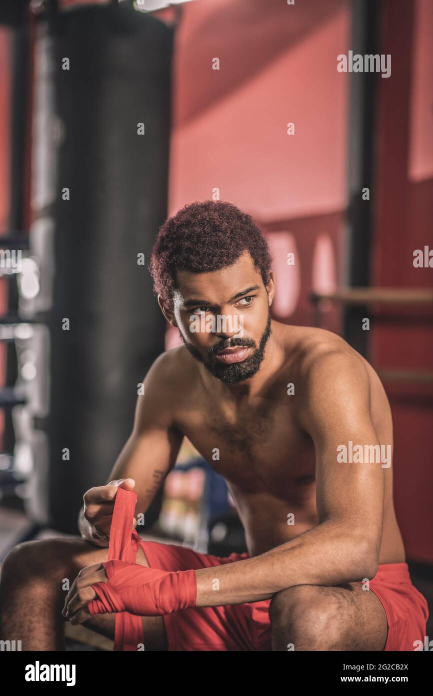 African american kickboxer typing a bandage on his hand before the ...