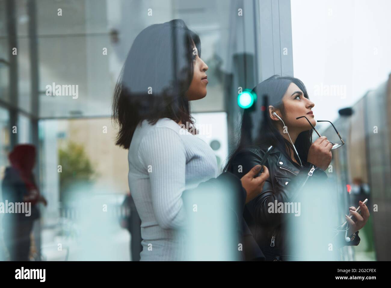 Female friends at bus stop Stock Photo - Alamy
