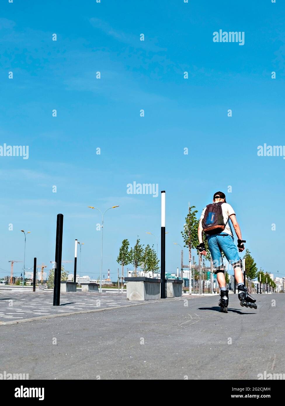Rear view of young man in blue shorts with backpack, in protective ...