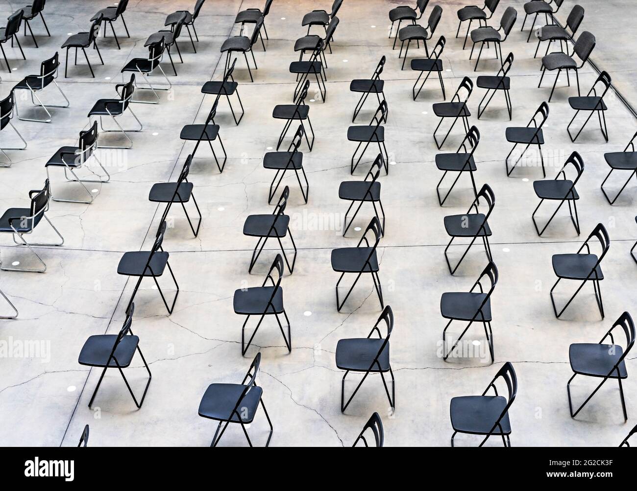 Many black chairs standing indoors at the same distance before the ...