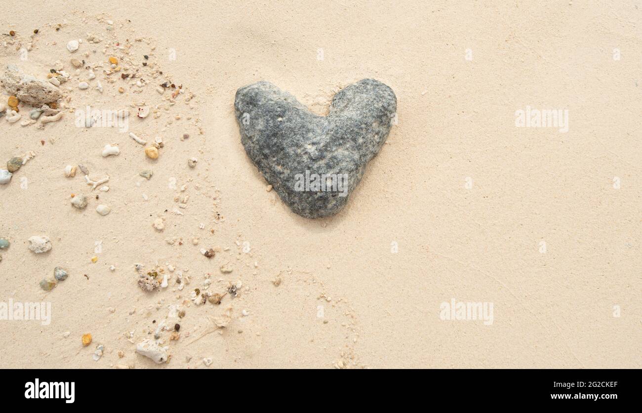 Heart-shaped pebble buried in sand beach Stock Photo - Alamy