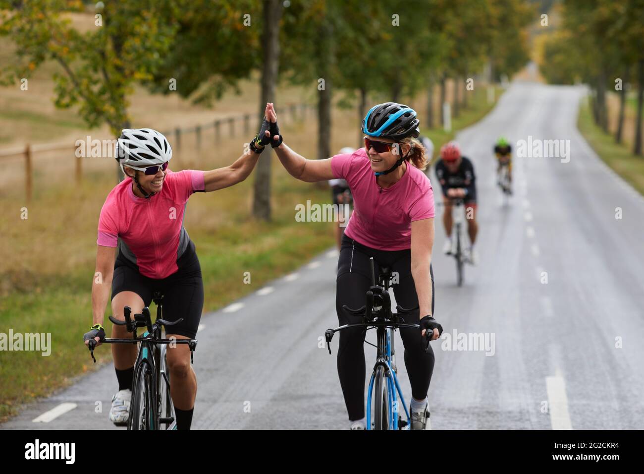 Smiling female cyclist giving each other high five Stock Photo - Alamy