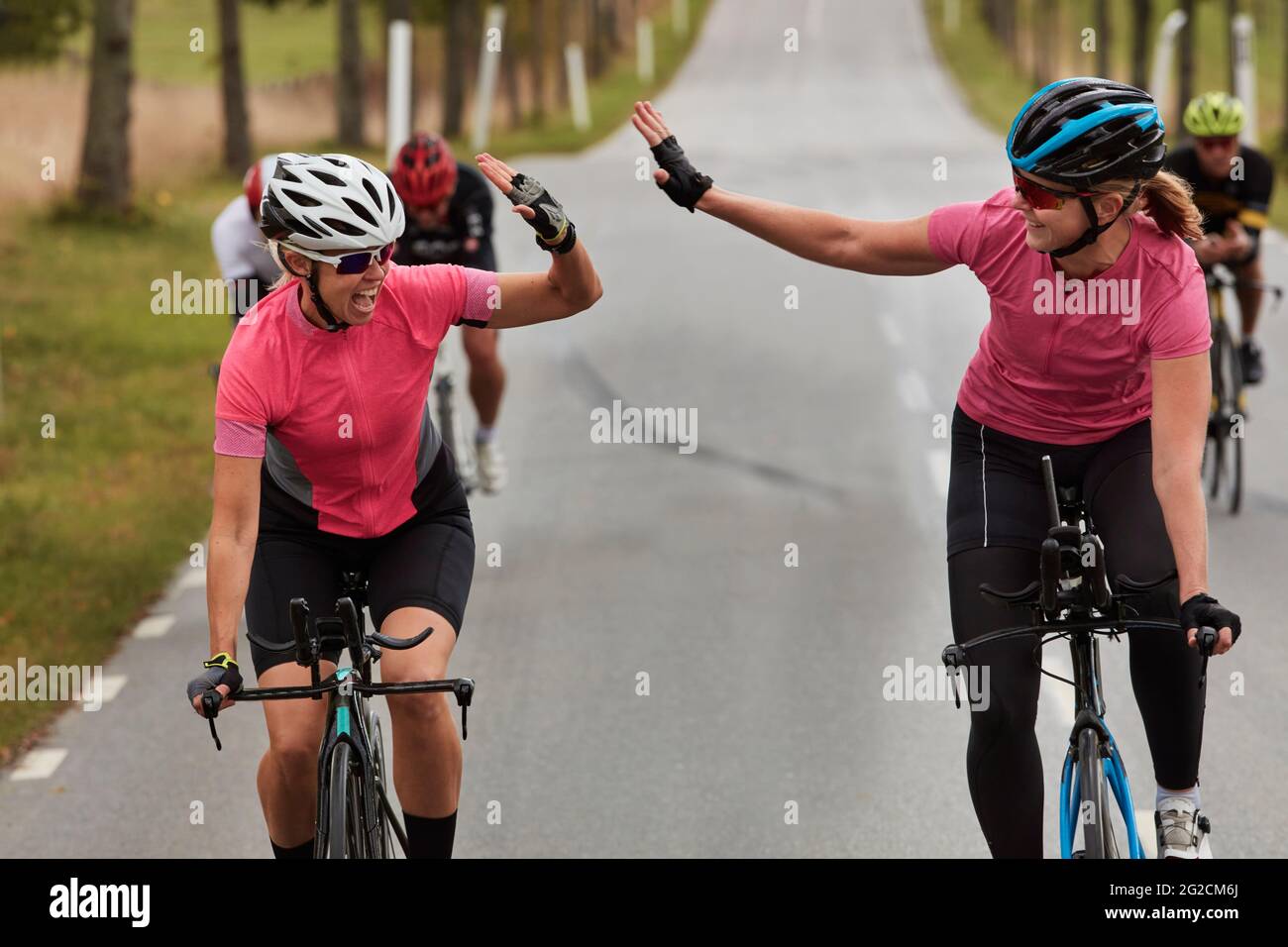 Happy cyclists giving each other high five Stock Photo - Alamy