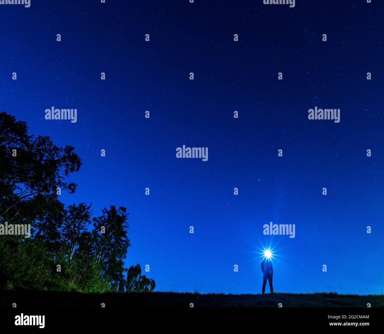 Man with light on his head standing alone at night Stock Photo - Alamy