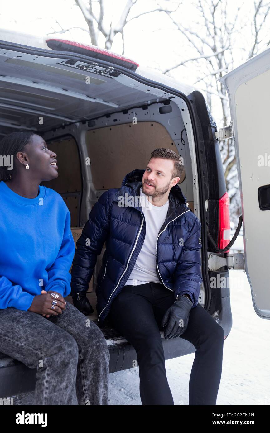 Couple sitting in open van Stock Photo - Alamy
