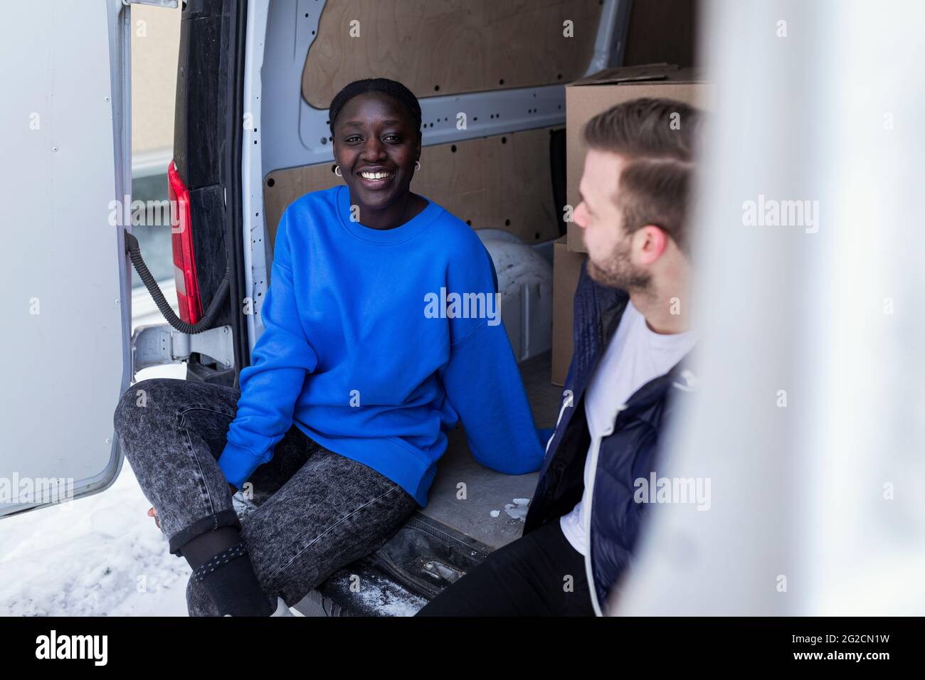 Couple sitting in open van Stock Photo - Alamy