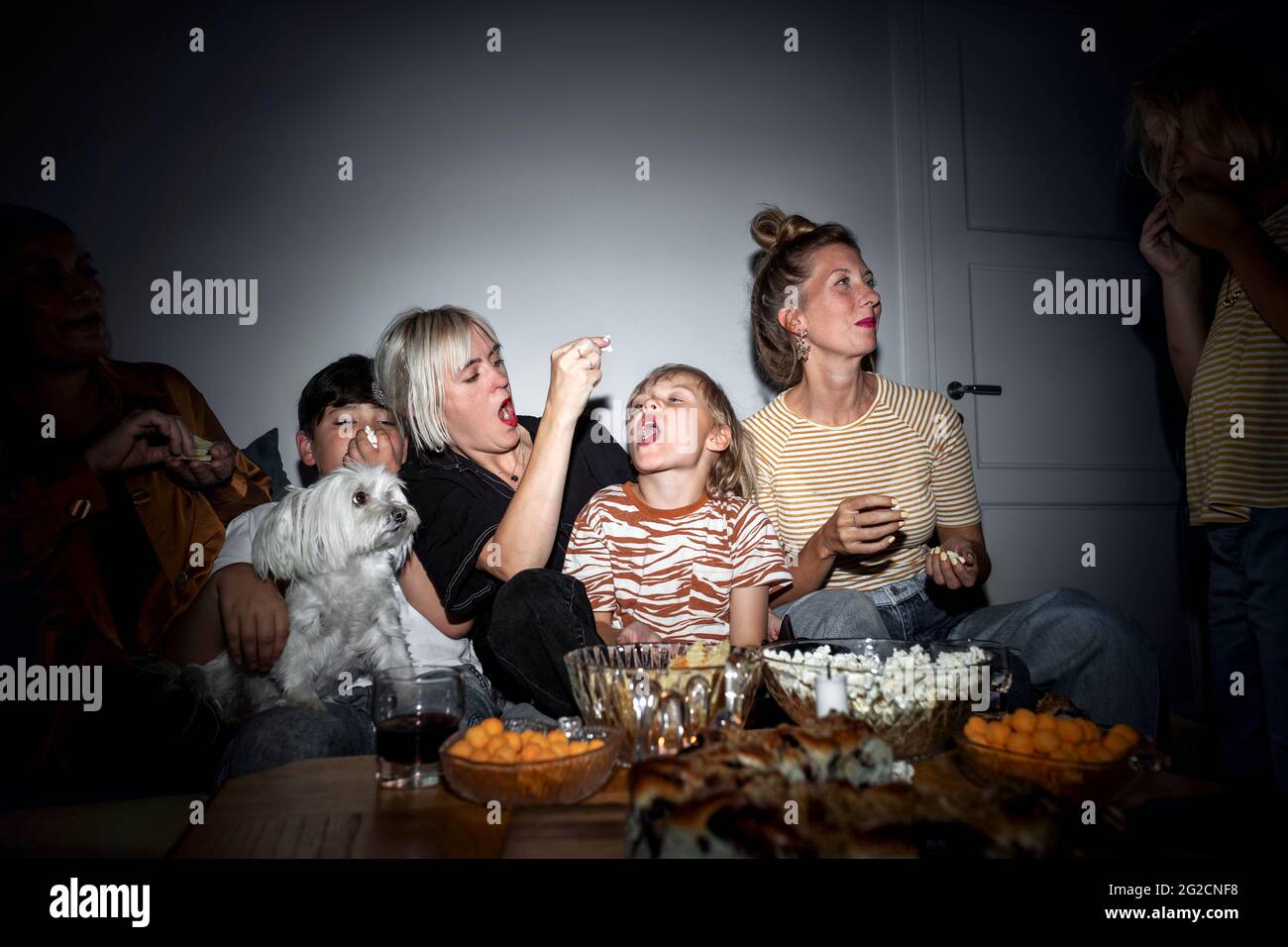 Family with kids snacking in living room Stock Photo - Alamy