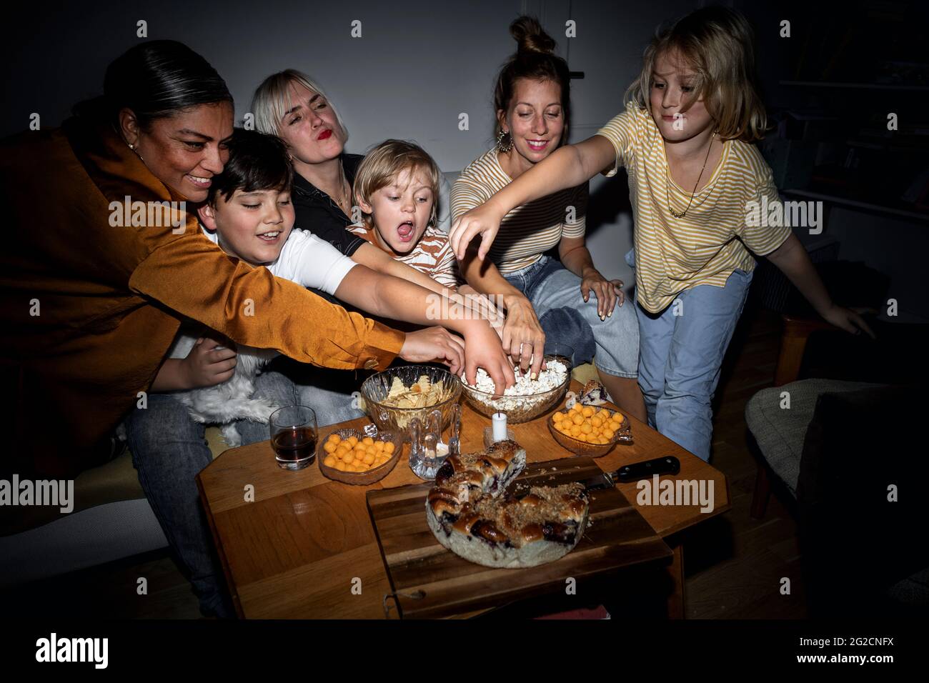 Family with kids snacking in living room Stock Photo - Alamy