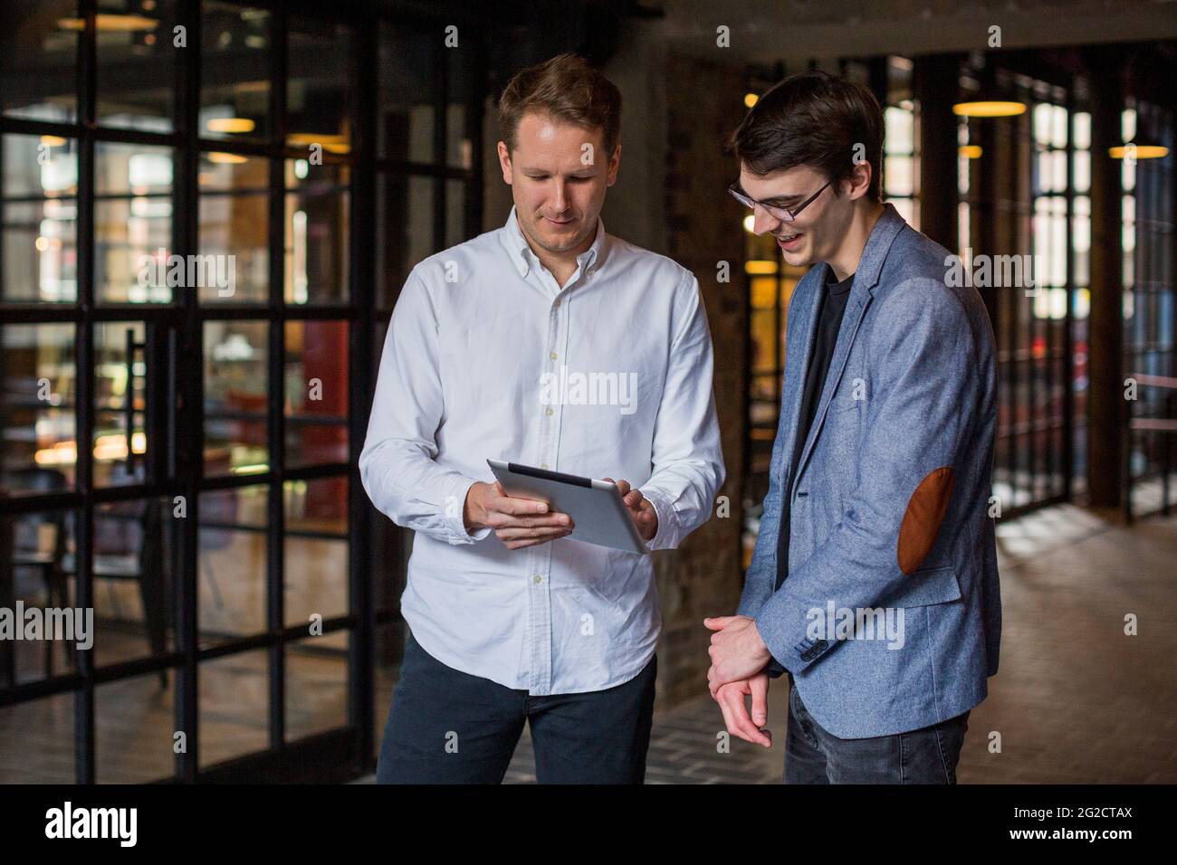 Two men standing in modern interior and discussing Stock Photo - Alamy