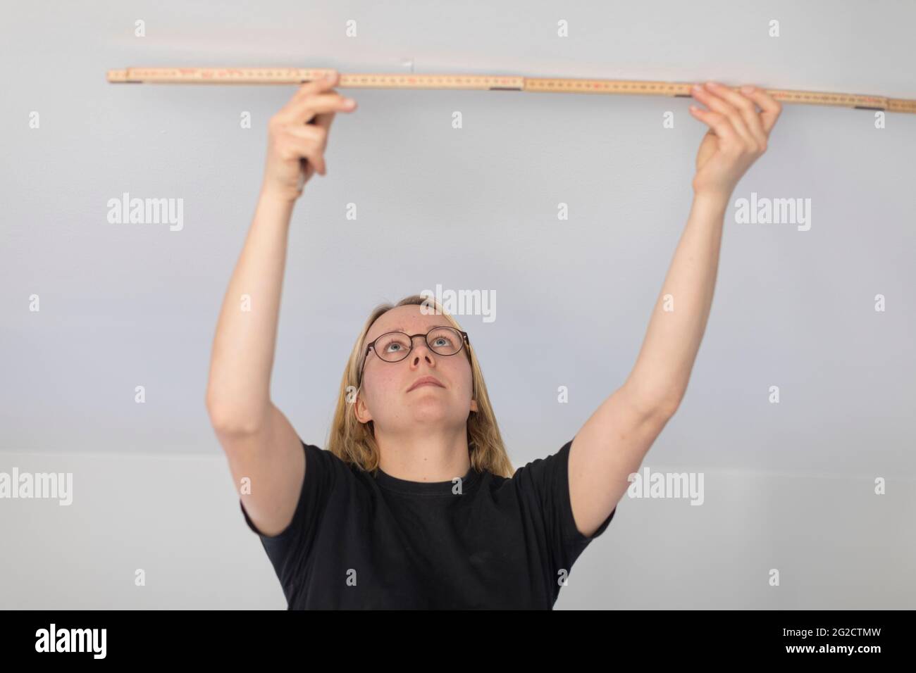 Woman measuring ceiling with folding ruler Stock Photo - Alamy