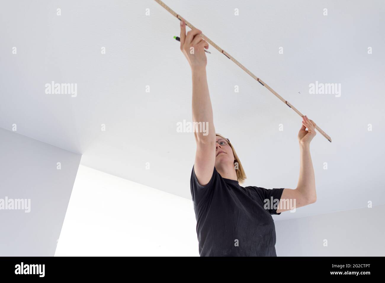 Woman measuring ceiling with folding ruler Stock Photo - Alamy