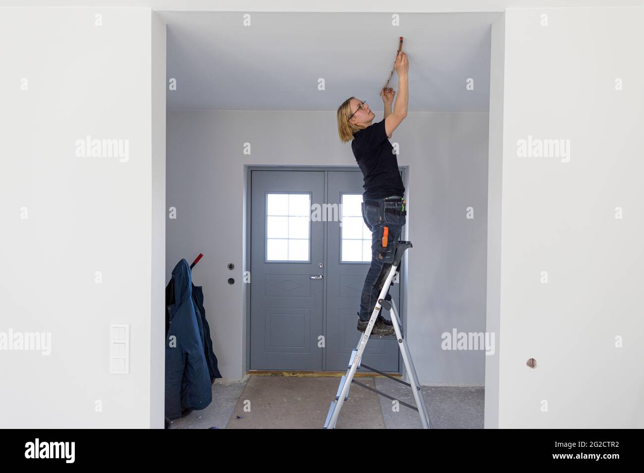 Woman measuring ceiling with folding ruler Stock Photo - Alamy