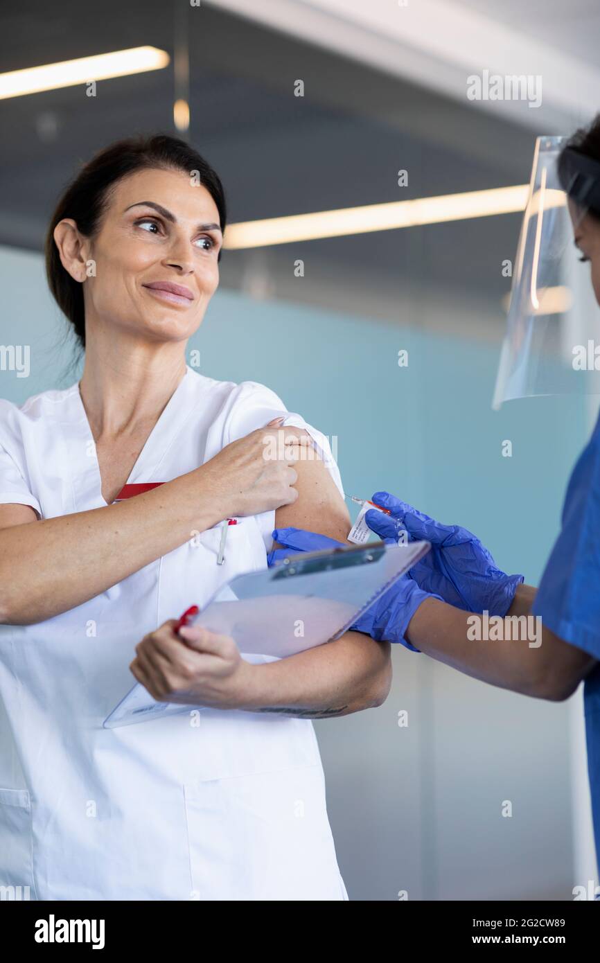 Female doctor receiving covid-19 vaccine Stock Photo - Alamy
