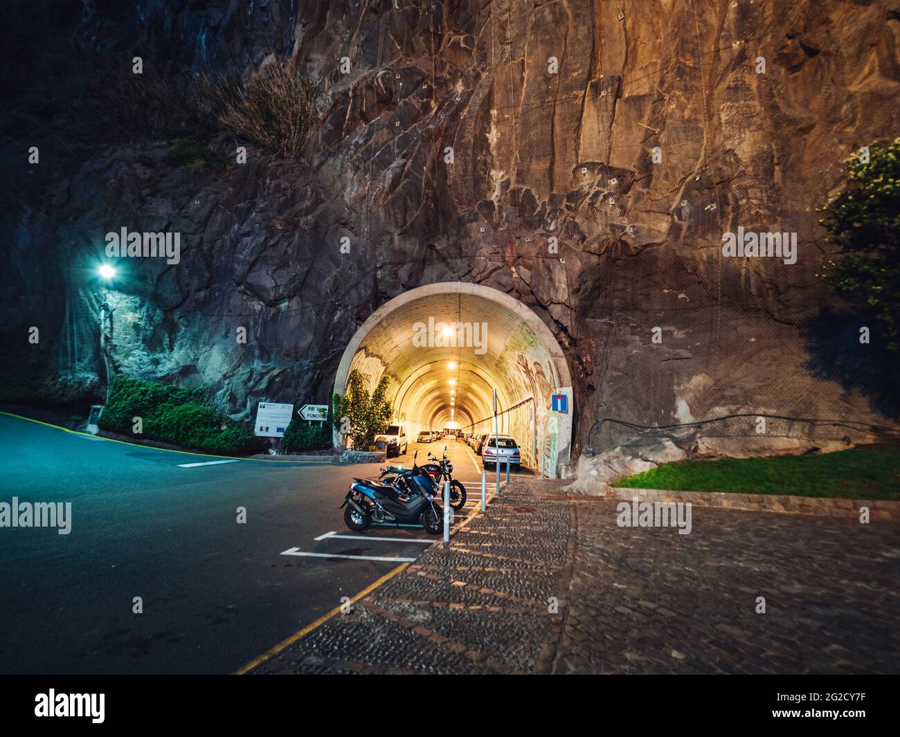 Motorcycles in front of a tunnel in the rocks with cars and bright ...