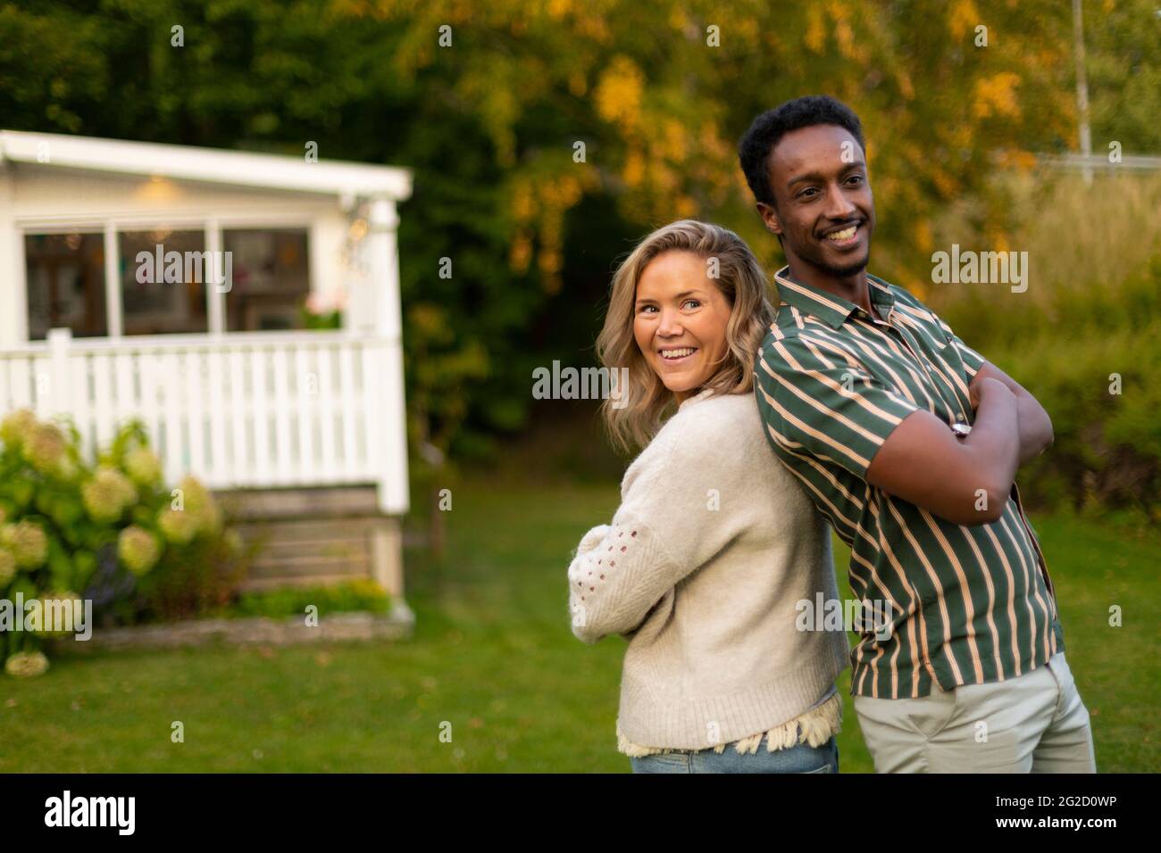 Happy friends standing back to back Stock Photo - Alamy