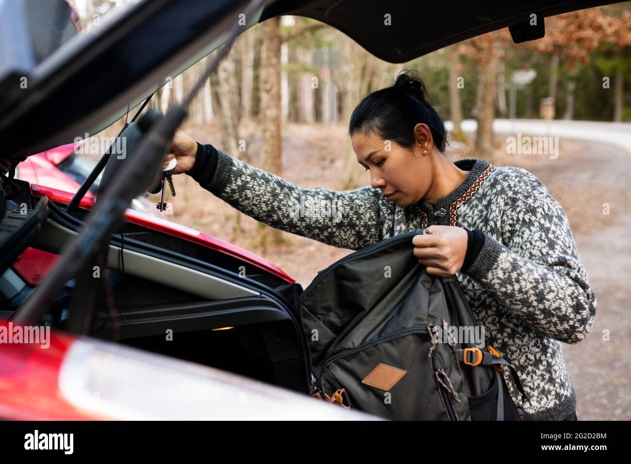 Woman putting backpack in car trunk Stock Photo - Alamy