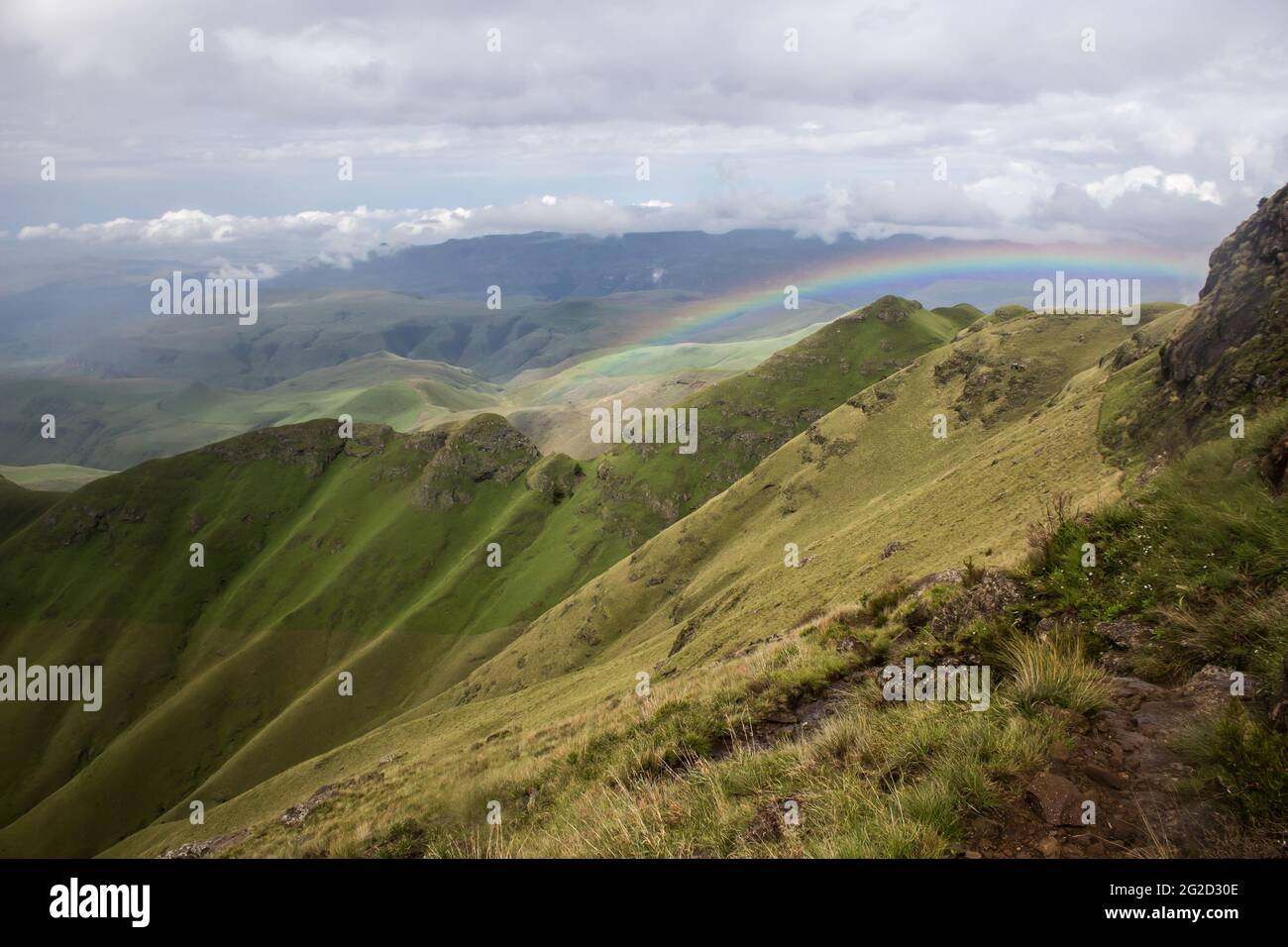 A majestic, clear, rainbow, arching over a grass covered ridge in the ...