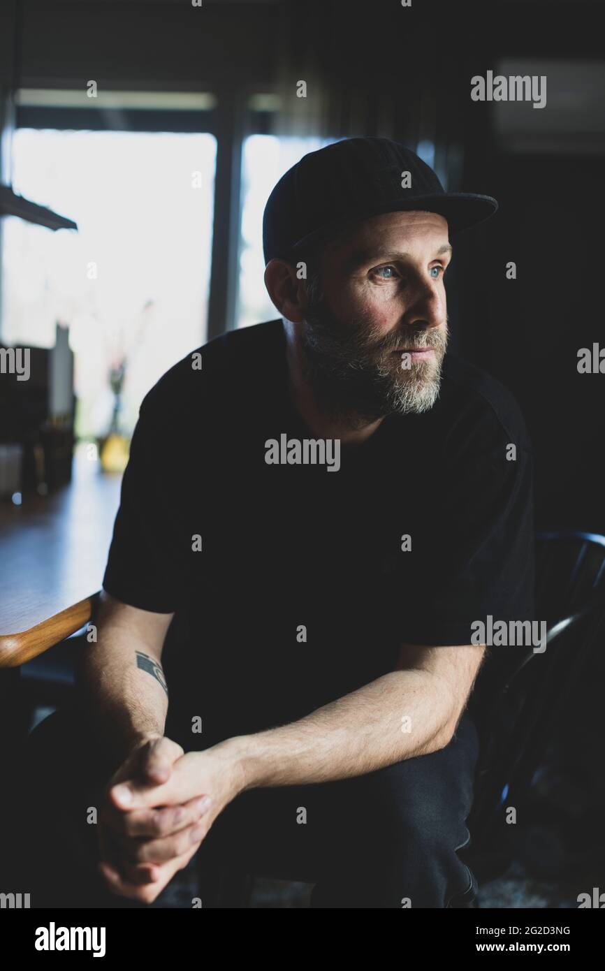 Man in baseball cap sitting in chair Stock Photo - Alamy