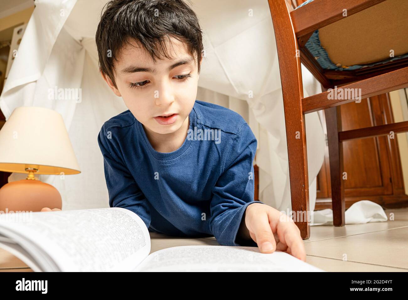 cute lonely caucasian child reading a book at home in isolation Stock ...