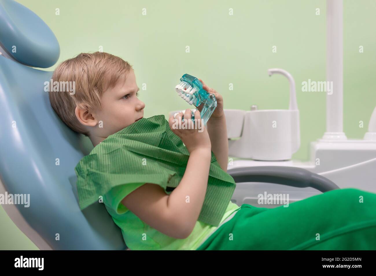 Boy man child at dentist in chair look at white teeth. Curious, serious ...