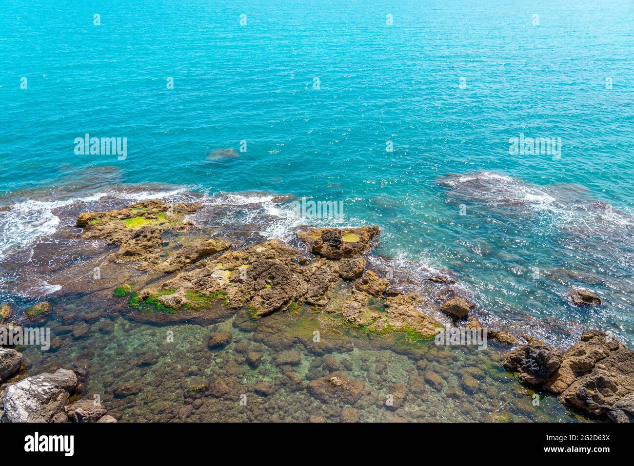 Many big and small rocks and sea waves hitting the rocks. Blue sea ...