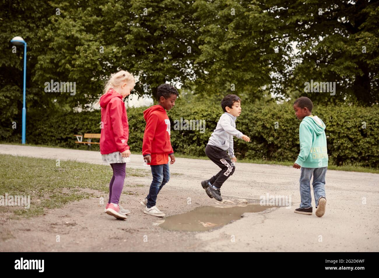 Children jumping over puddle Stock Photo - Alamy