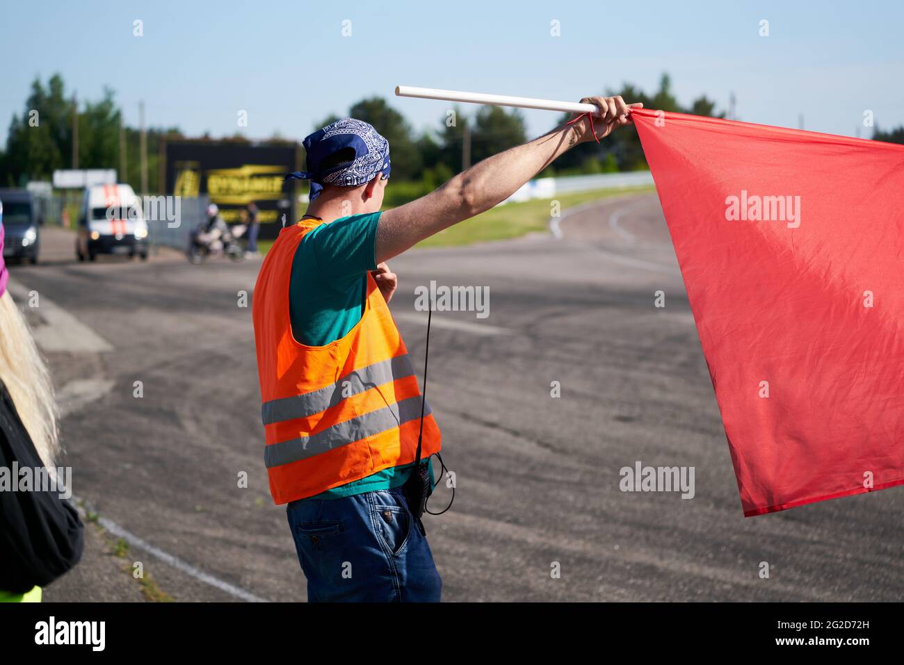 A marshal at a racetrack holds up a red flag to the rider(s Stock Photo ...