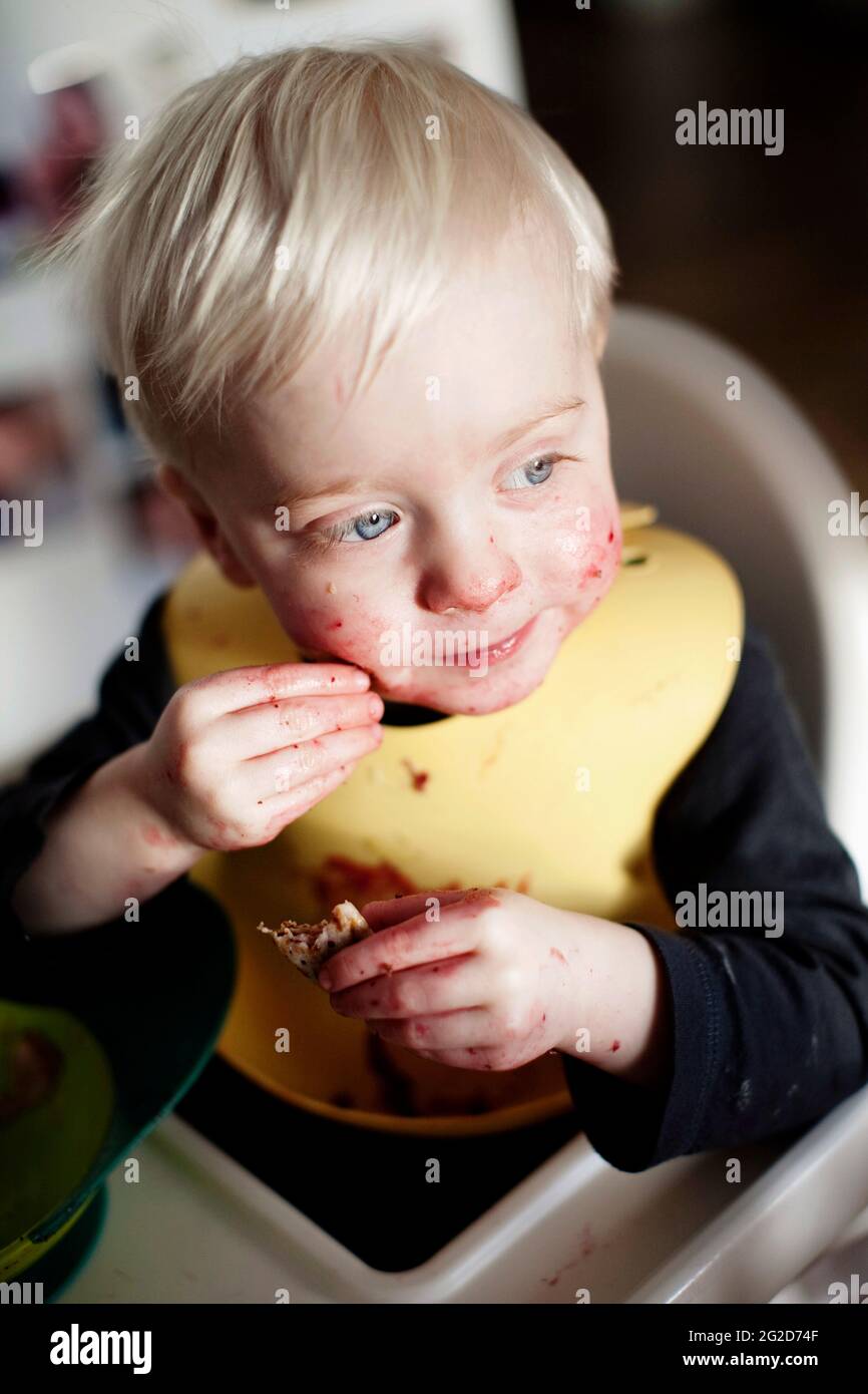 Boy in high chair eating Stock Photo - Alamy