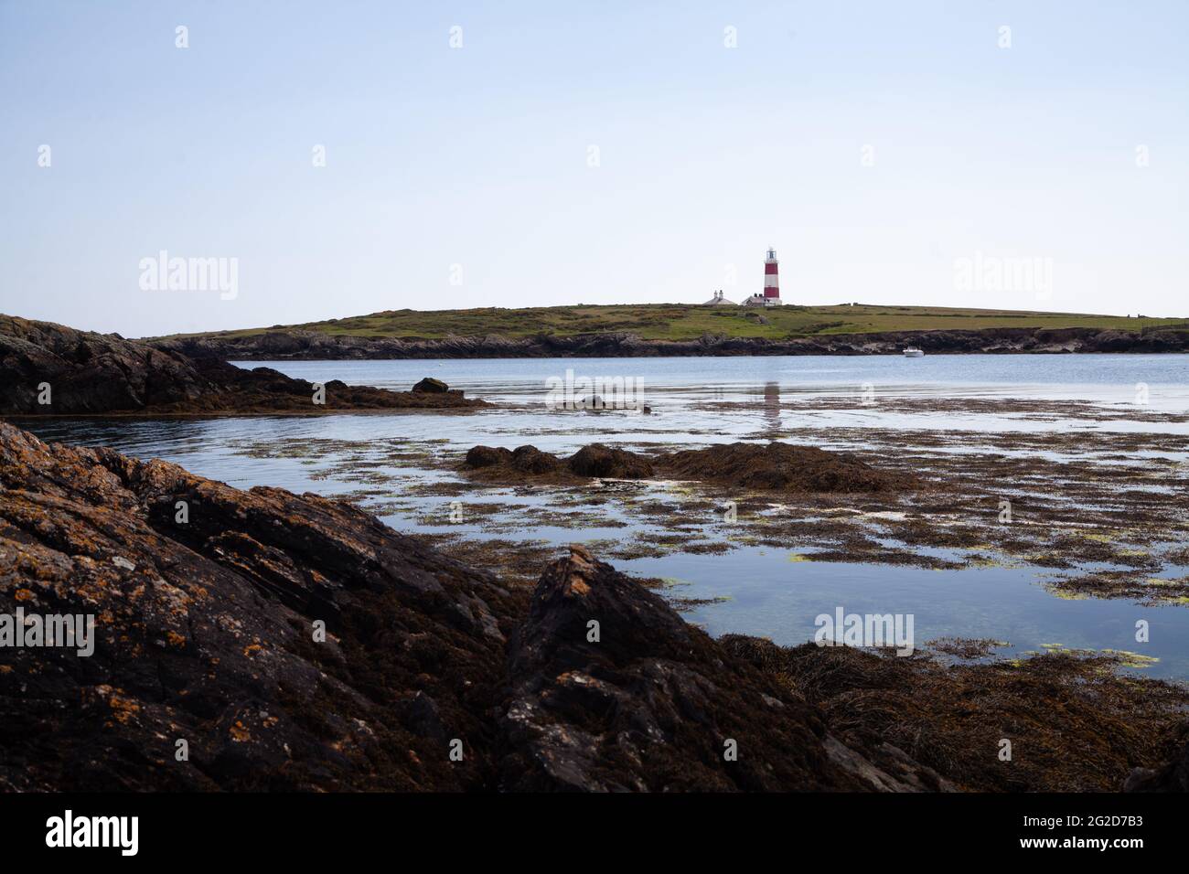 View across a rocky bay near Y Cafn; Ynys Enlli / Bardsey Island wharf ...