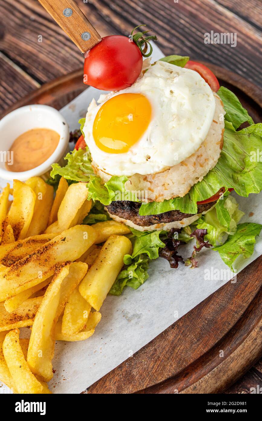 Korean burger with sunny side up egg, rice and fried fries on wooden ...