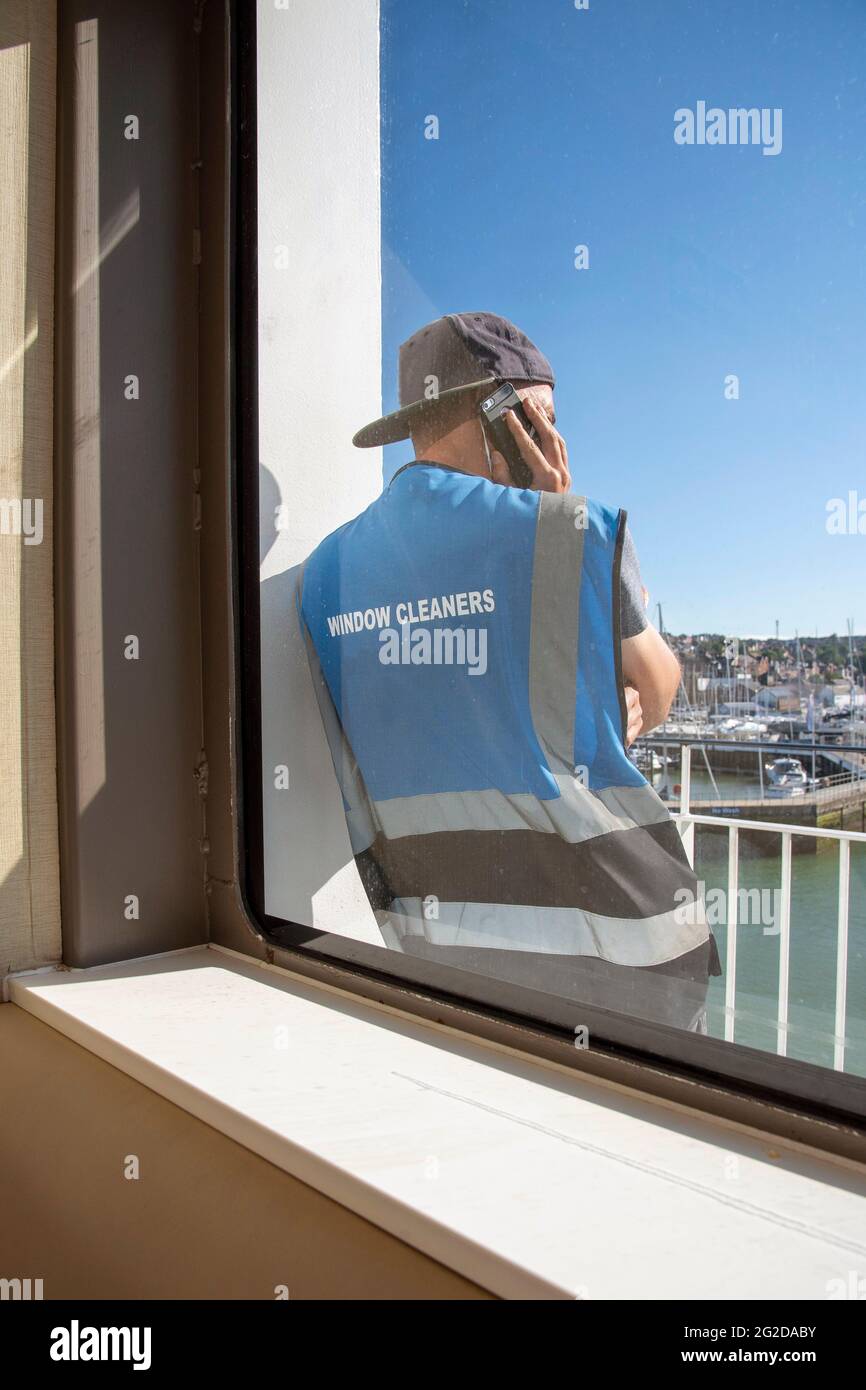 Isle of Wight, UK. 2021. Male window cleaner taking a break from ...