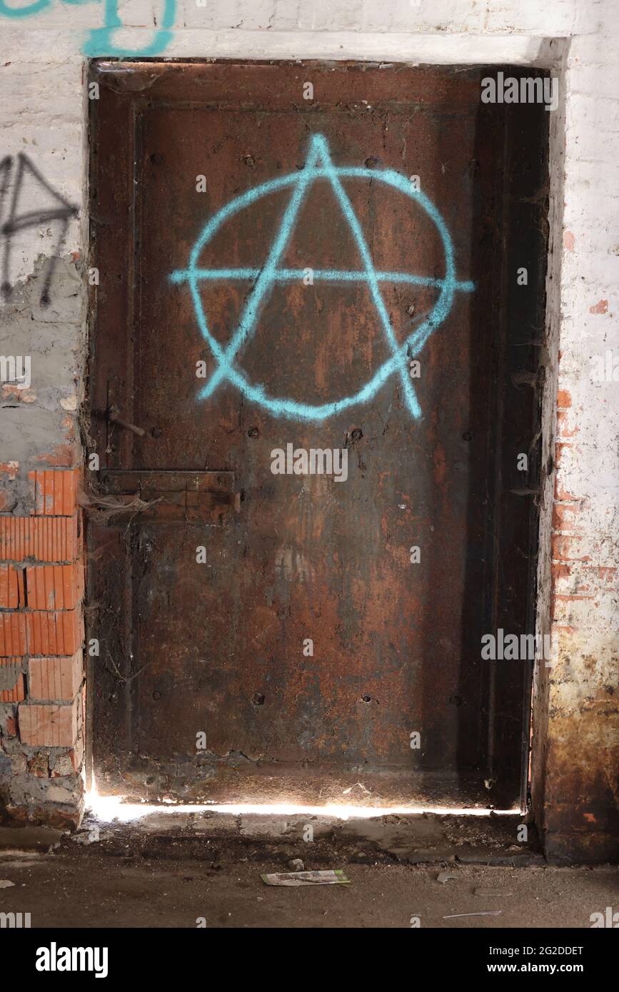 Rusty old metal door of an abandoned building with a blue anarchy ...