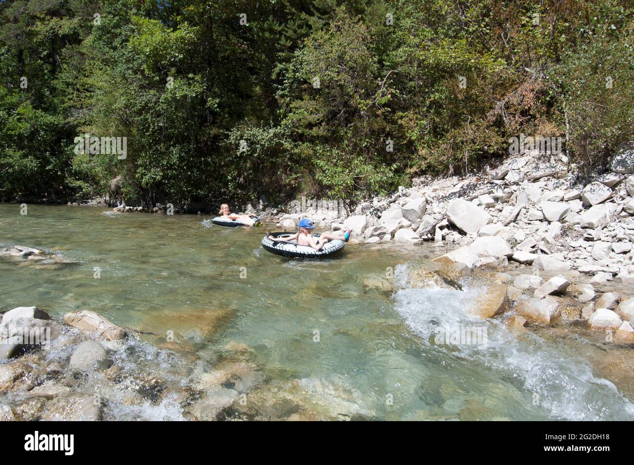 A kid floats down the rapids on a river in France on a rubber ring ...